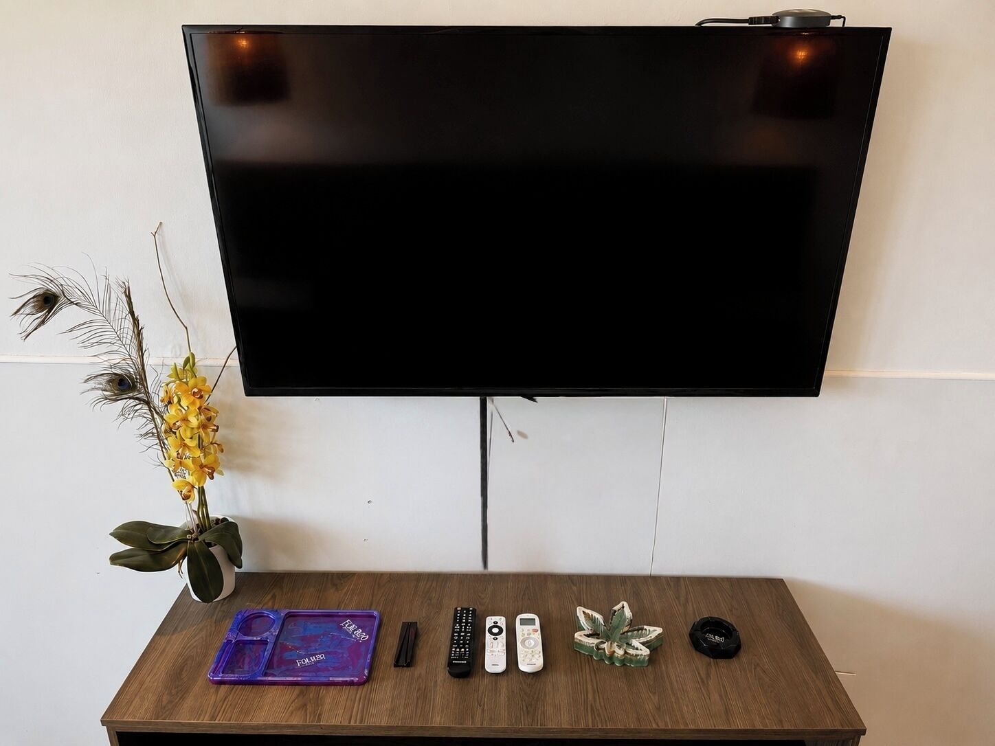 Uma televisão de tela plana presa na parede com uma mesa de madeira na frente.