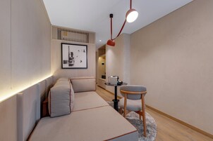Quarto moderno com sofá, uma cadeira, uma mesinha e um quadro na parede.