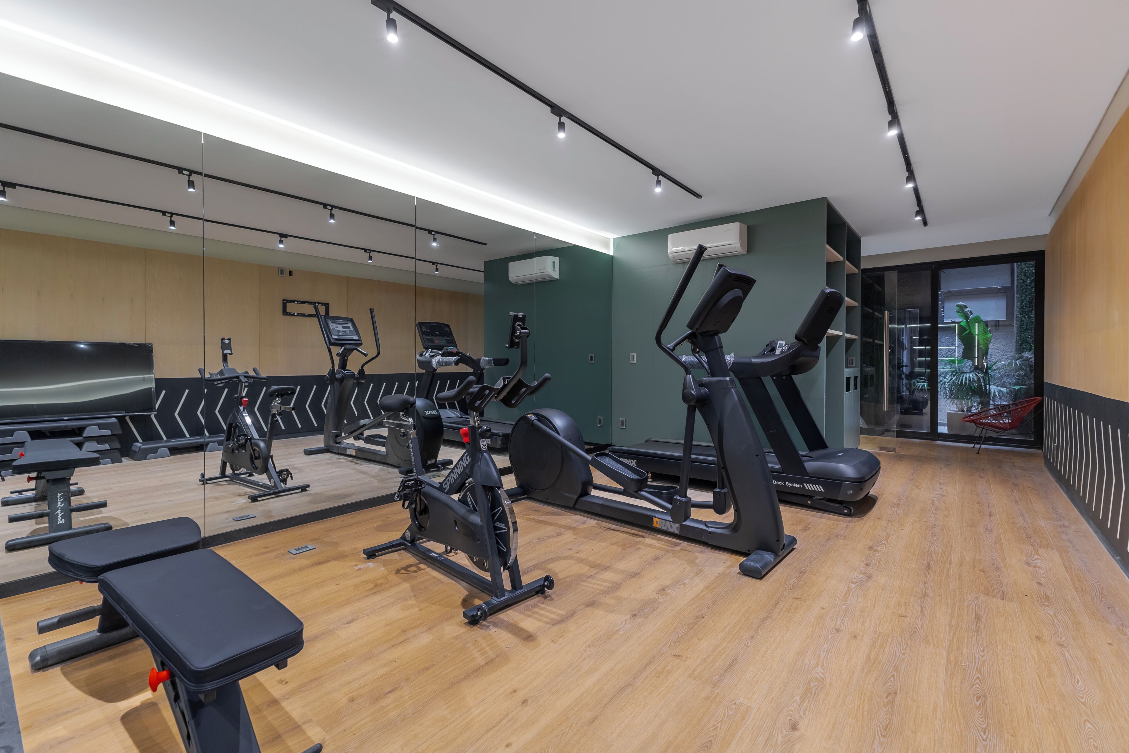 Uma academia com diversos equipamentos de ginástica, um banco e um espelho grande.