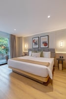 Quarto moderno com uma cama grande, uma mesinha de cabeceira, um criado-mudo e uma luminária na parede.