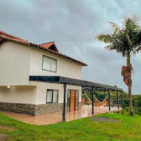 Uma casa moderna com telhado de cerâmica, varanda coberta e uma palmeira.