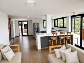 Cozinha moderna com ilha central, banquetas e vista para o verde lá fora.