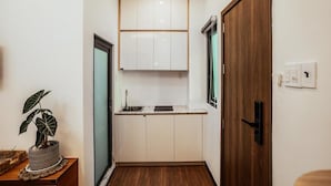 Uma cozinha compacta com armários brancos, uma porta de madeira e uma pia pequena.