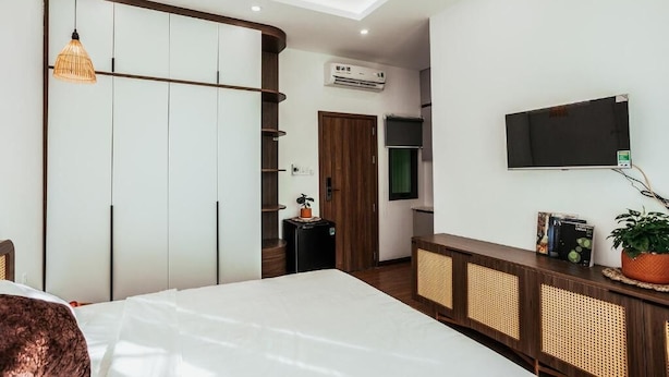 Quarto moderno com cama, televisão, guarda-roupa e um pequeno espaço de trabalho.