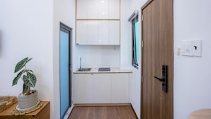 Uma cozinha compacta com armários brancos, uma pia e uma porta de madeira.
