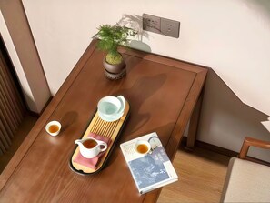 Uma mesa de madeira com um vaso de planta, um tabuleiro com xícaras de chá e um bule.