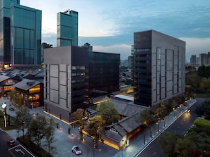 Uma área urbana moderna com edifícios altos, uma passarela para pedestres e uma rua com veículos.