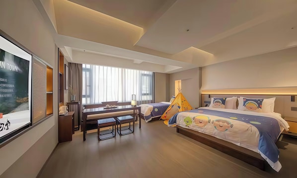 Quarto de hotel com uma cama, uma escrivaninha e uma cadeira. Há uma janela com cortinas, uma televisão e uma luminária na parede.