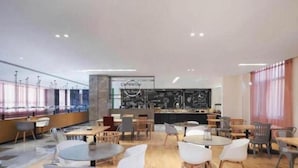 Um café moderno com mesas e cadeiras redondas, um cardápio em lousa e um balcão.