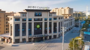 Um hotel chamado Campanile com um design arquitetônico moderno, apresentando uma entrada imponente e uma fachada de vidro ampla.