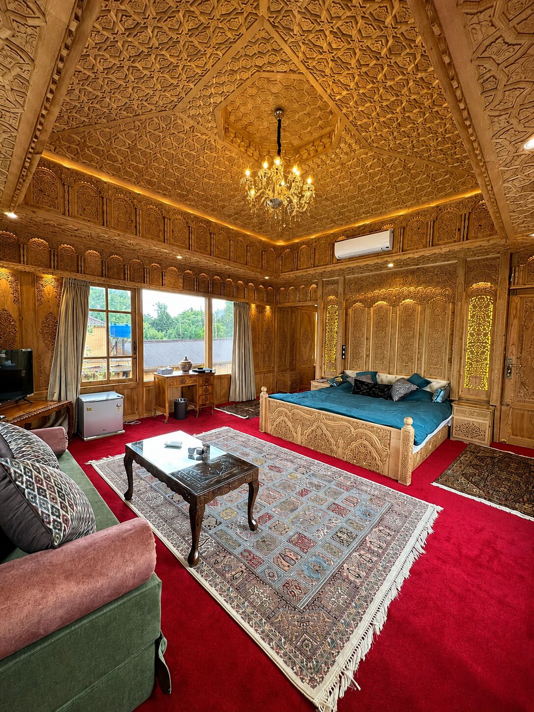 Quarto com uma cama grande, um sofá, uma mesa de centro e um candelabro.