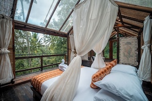 Quarto com cama, cortinas e vista para o exterior.