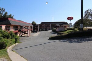 Um motel com fachada vermelha, área de estacionamento coberta e placa visível do Executive Inn.