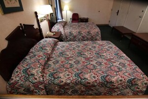 Quarto de hotel com duas camas, uma escrivaninha, uma cadeira e um guarda-roupa.