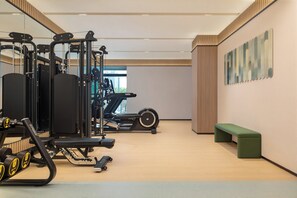 Uma academia com equipamentos de exercício, uma bicicleta ergométrica e um banco.