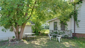 A backyard with a picnic table, a chair, a small shed, and a tree.