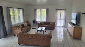 Uma sala de estar com dois sofás, uma mesa de centro, uma televisão e um ventilador.