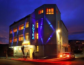 Um edifício de vários andares com uma placa na fachada que diz 'HOTEL' e 'XOTEL'.
