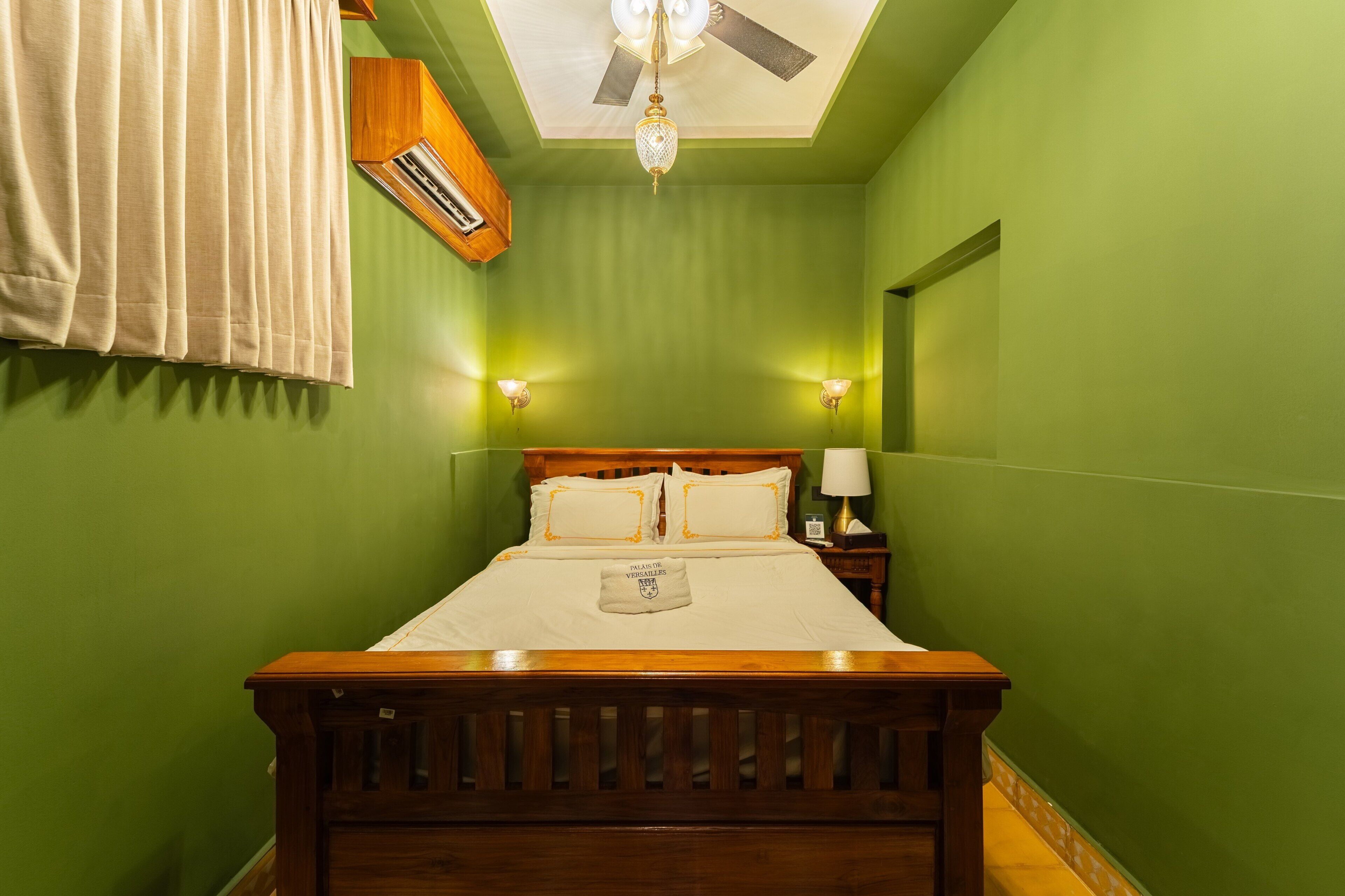 Quarto com cama, ventilador de teto e duas luminárias de parede.