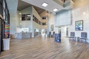 Um hall amplo com piso de madeira, um balcão de recepção e uma área de estar com cadeiras.