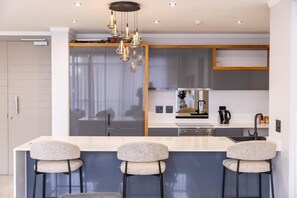 Uma cozinha moderna com uma ilha central, banquetas e iluminação pendente.
