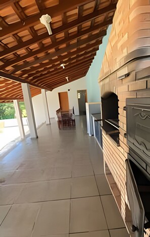 Uma área de pátio externa com lareira de tijolos e teto de madeira.