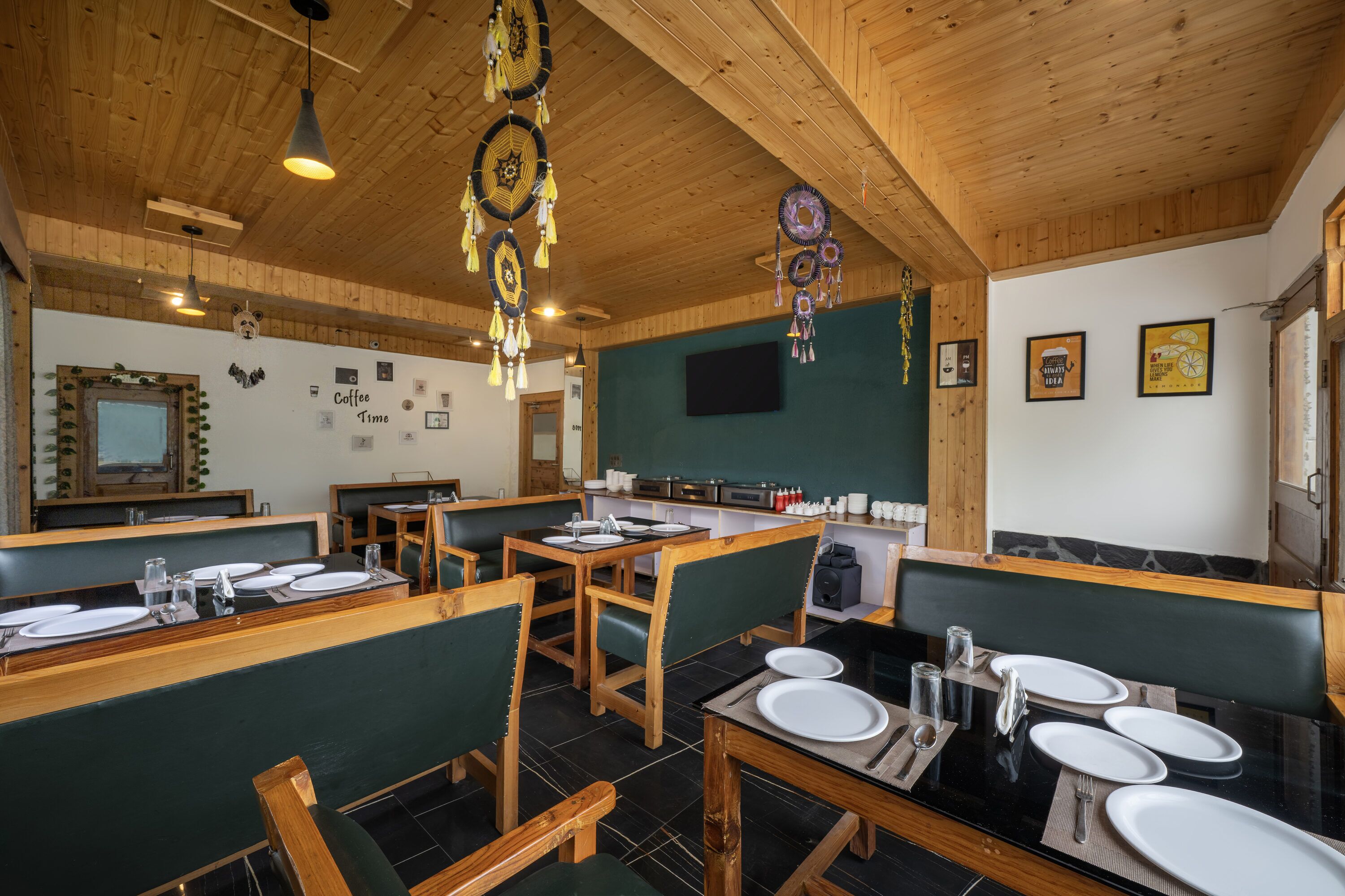 Um restaurante com interiores em madeira, cabines verdes e chão de azulejos pretos.