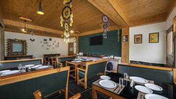 Um restaurante com interiores em madeira, cabines verdes e chão de azulejos pretos.