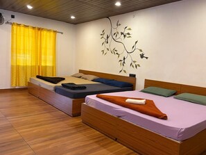 Quarto com duas camas, piso de madeira, cortina amarela e um mural na parede.
