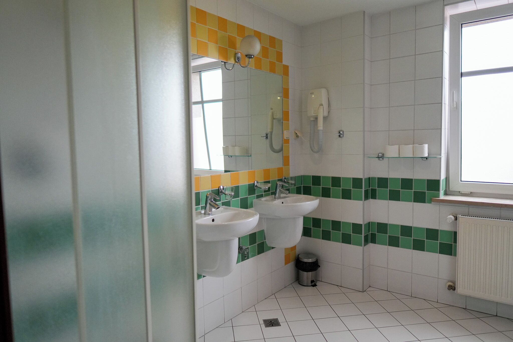 Casa de banho com duas pias, um espelho e uma janela.