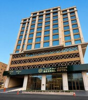 Um hotel de vários andares com uma entrada imponente, área de estacionamento e céu claro.