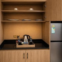 Uma cozinha compacta com armários de madeira, bancada preta e geladeira de aço inoxidável.