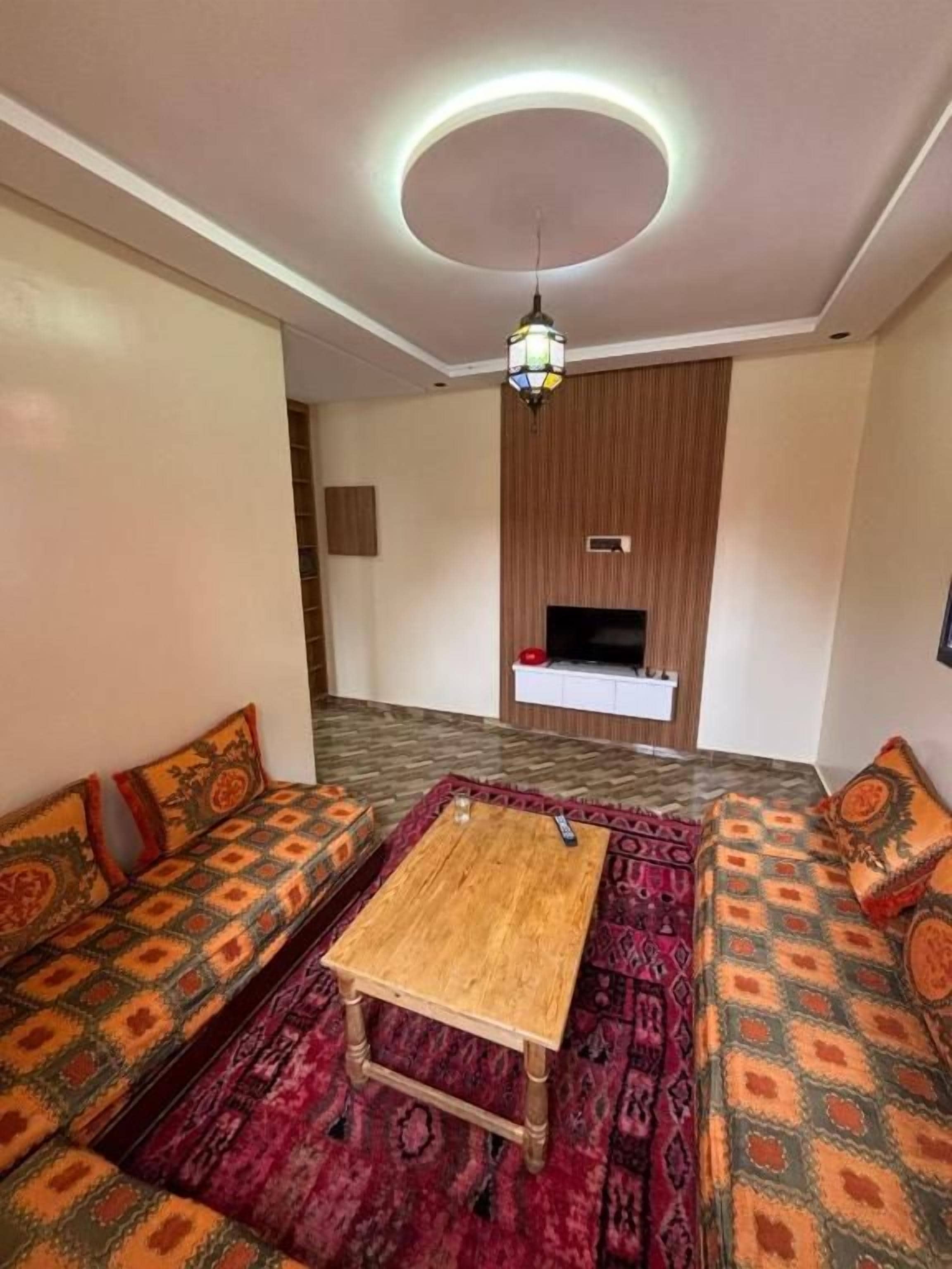 Uma sala de estar com sofá, mesa de centro, lareira e luminária no teto.