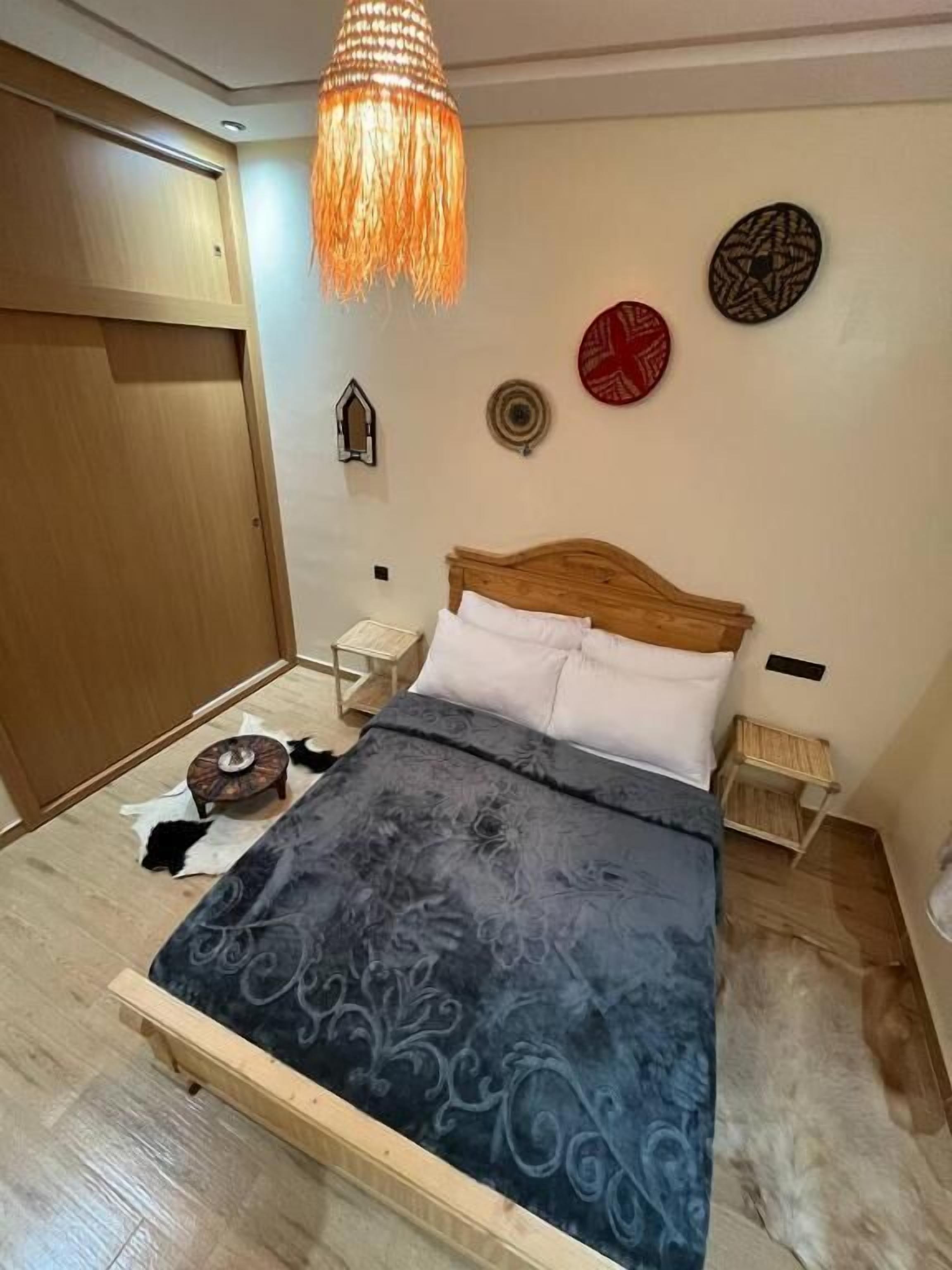 Um quarto com cama de madeira, luminária pendente e arte decorativa nas paredes.