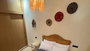 Um quarto com cama de madeira, luminária pendente e arte decorativa nas paredes.