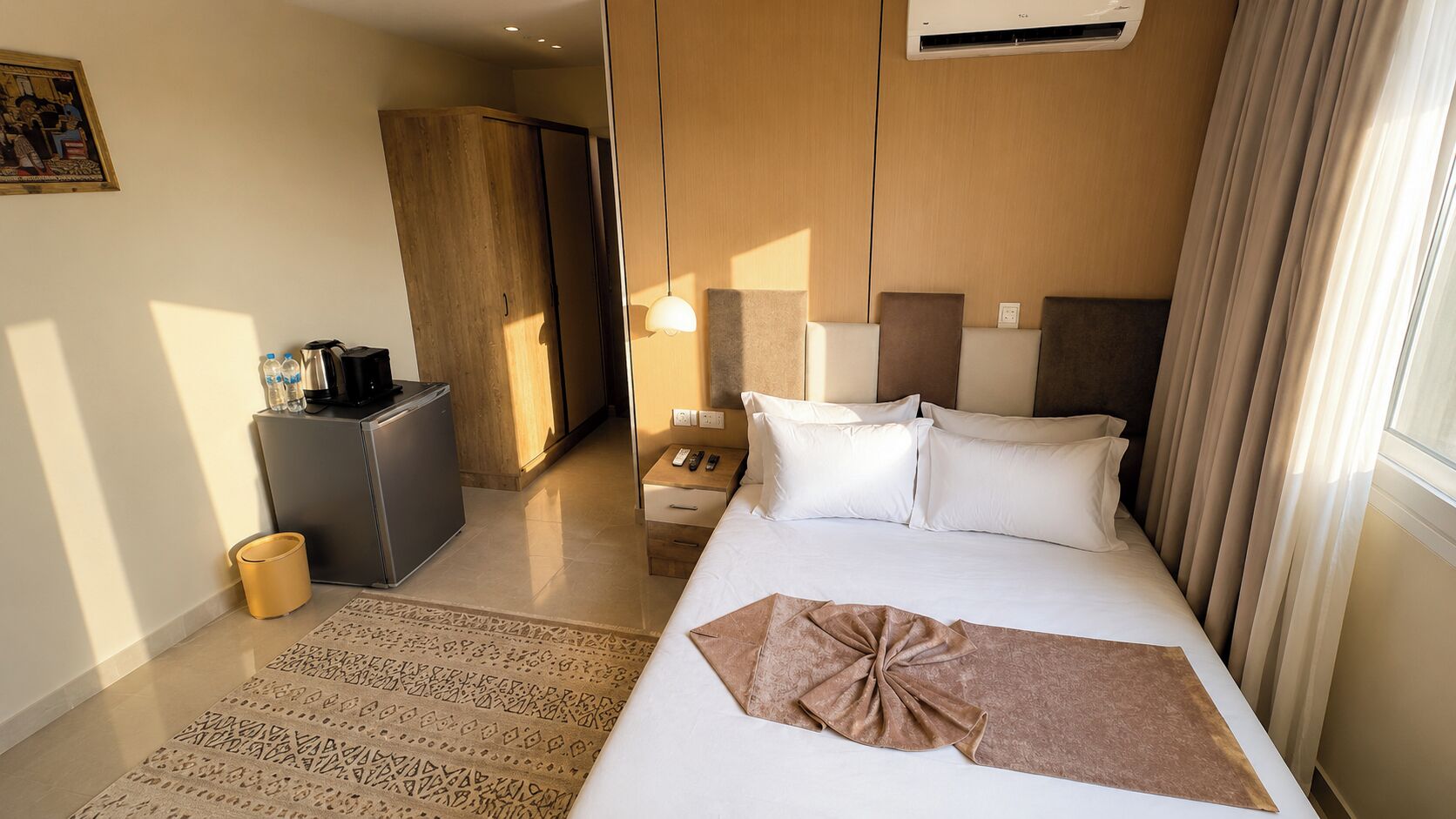 Quarto de hotel com cama, mesa de cabeceira e escrivaninha com cadeira.