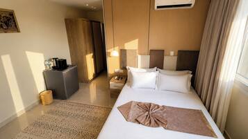 Quarto de hotel com cama, mesa de cabeceira e escrivaninha com cadeira.