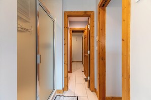 Um corredor estreito com portas de madeira e chão de azulejos.