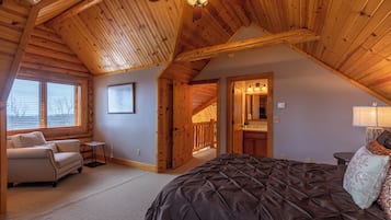 Quarto de cabana rústica com uma cama grande, um sofá e um ventilador de teto.