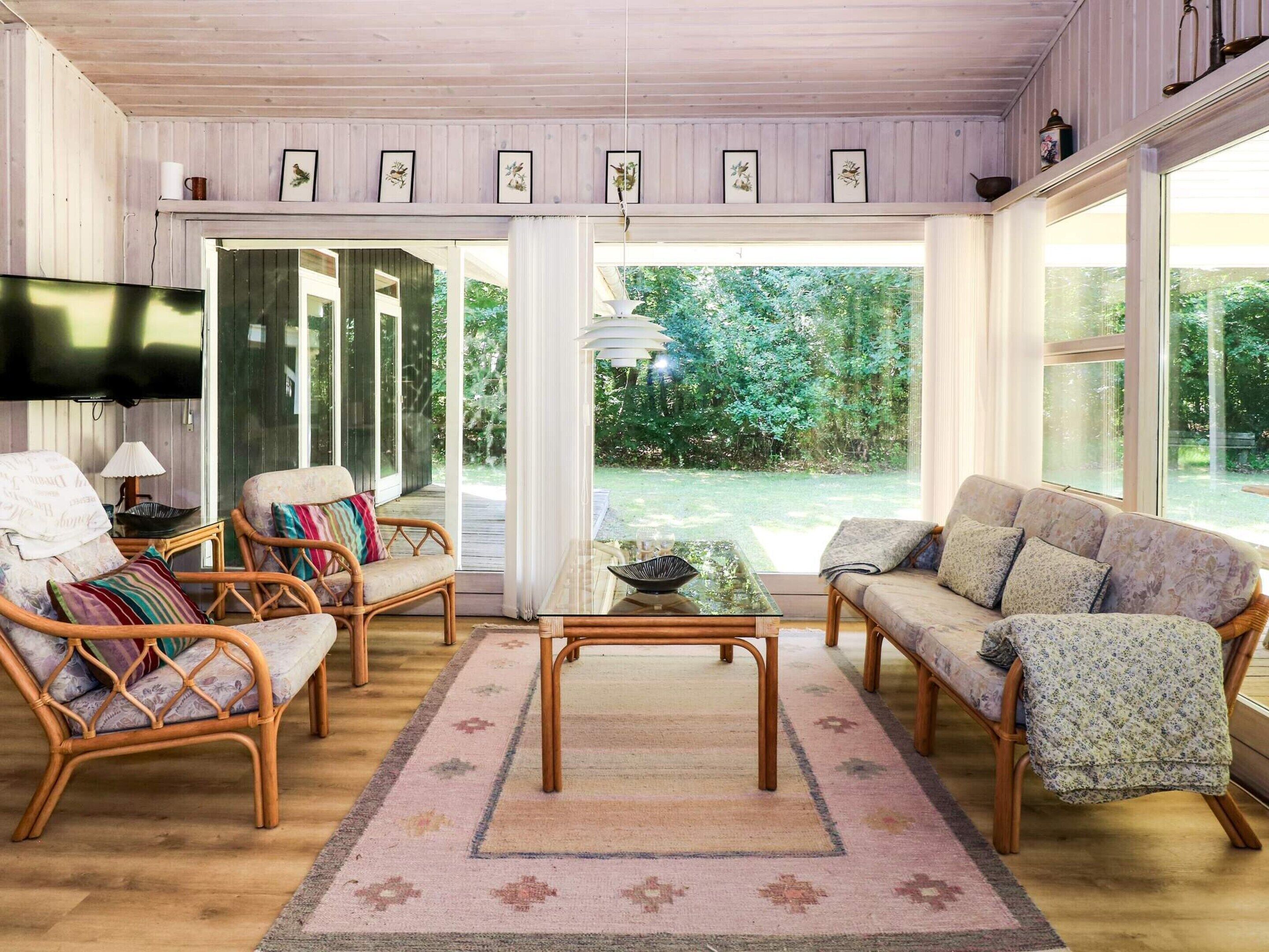 Um quarto aconchegante com móveis de vime, uma TV de tela plana e vista para um jardim.