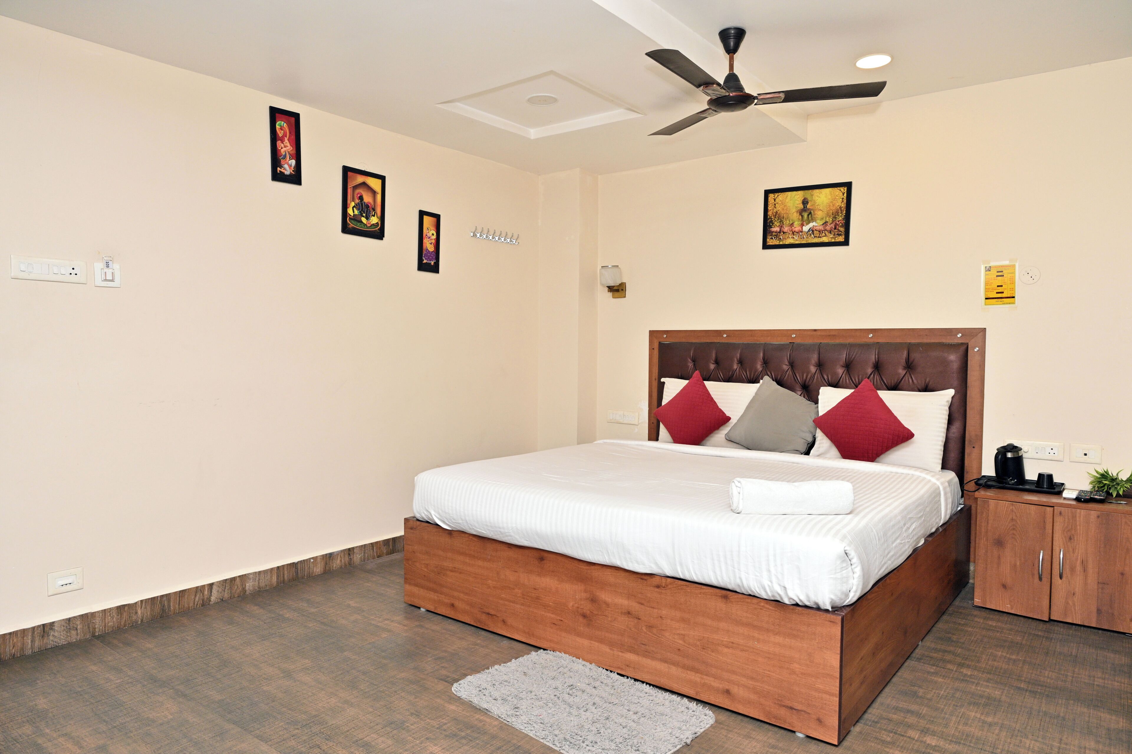 Quarto com cama de madeira, ventoinha no teto e mesa de cabeceira com cafeteira.