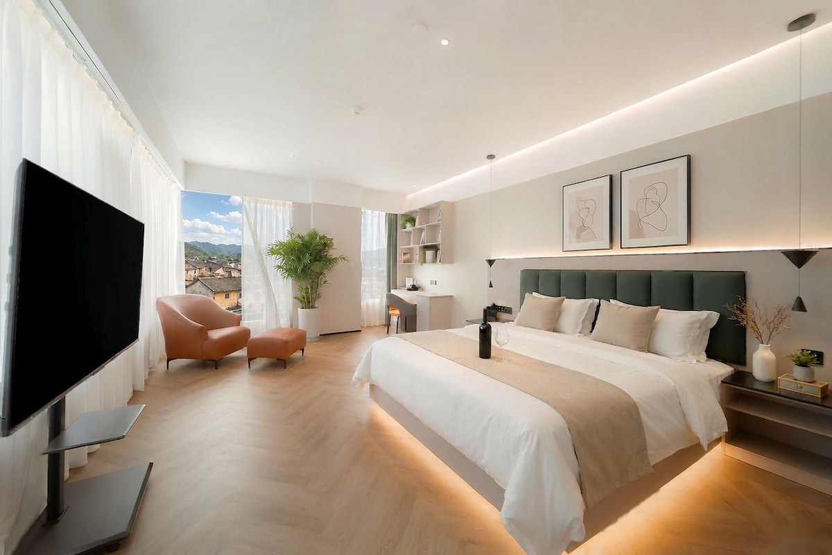 Quarto de hotel moderno com uma cama grande, televisão, escrivaninha e vista para o exterior.