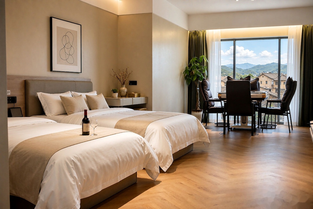 Quarto de hotel com duas camas, área de refeições e vista para as montanhas.