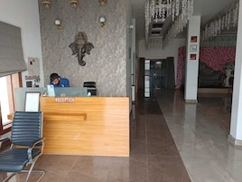 Uma receção com recepcionista, parede estampada e um candelabro.