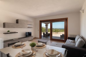 A modern kitchen with a dining area, a TV, and a view of the outdoors.