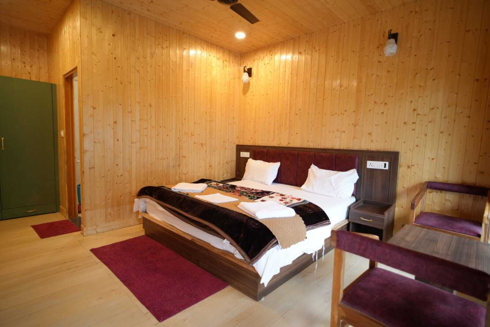 A wooden-paneled room with a bed, a nightstand, and a chair.