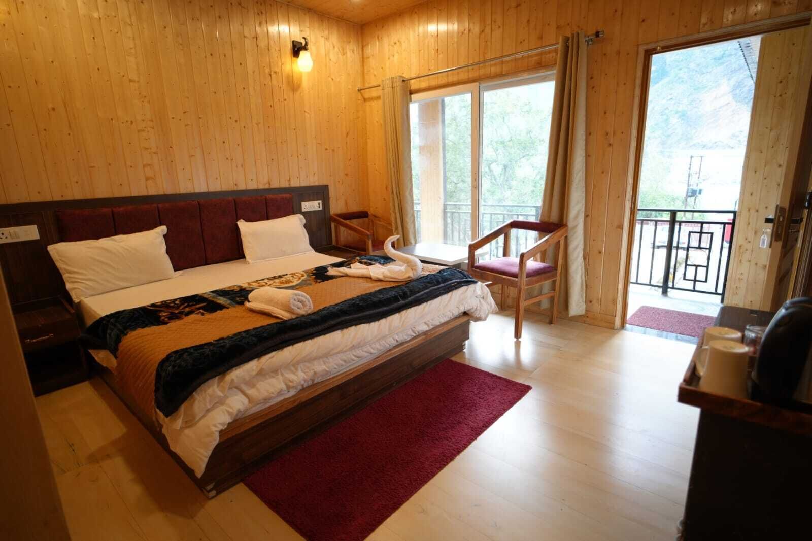 A wooden-paneled room with a bed, a chair, and a balcony.