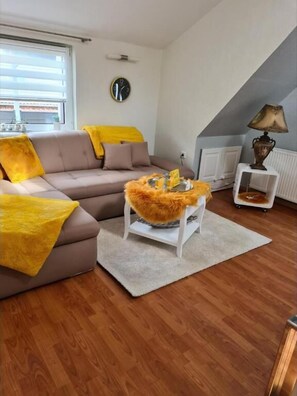Uma sala de estar com um sofá, uma mesa de centro, um abajur e um relógio na parede.