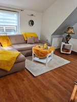 Uma sala de estar com um sofá, uma mesa de centro, um abajur e um relógio na parede.