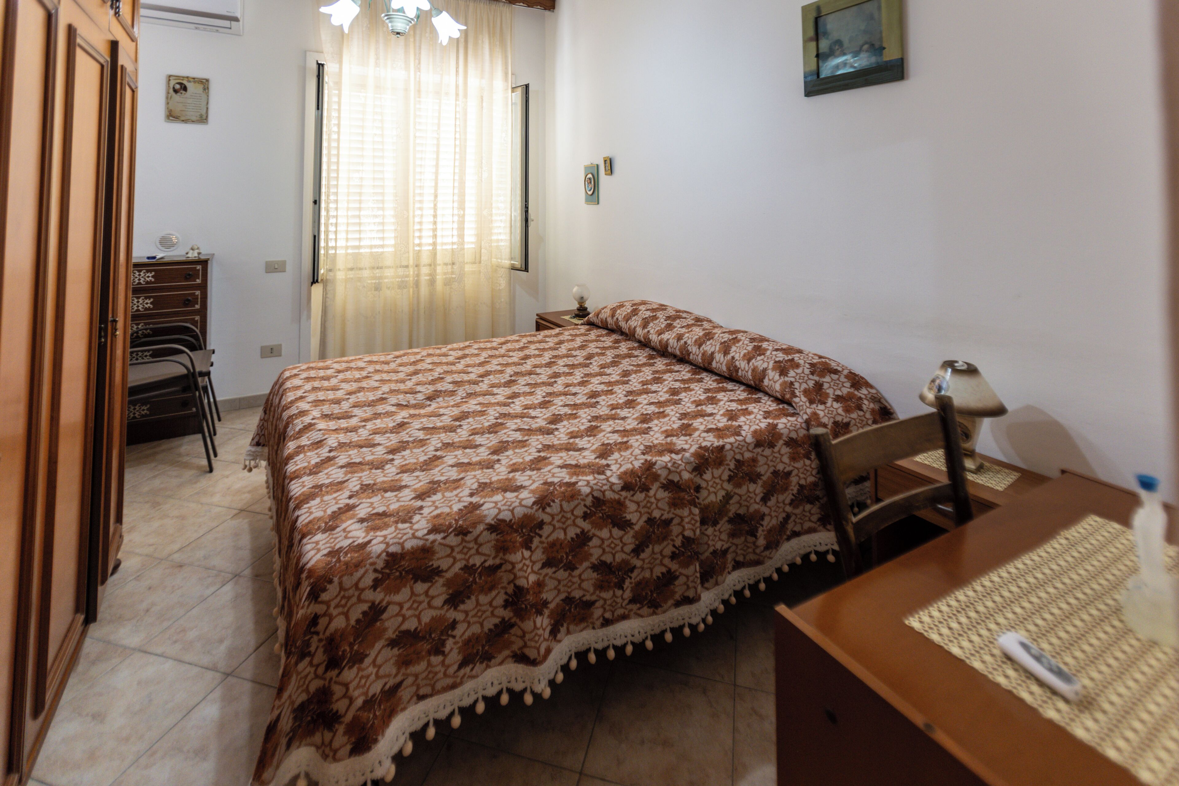 Um quarto com cama, escrivaninha, cadeira e guarda-roupa.